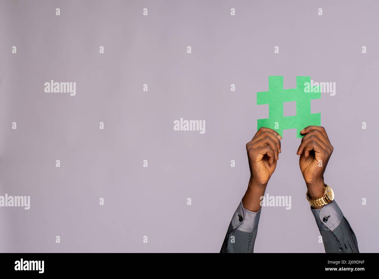 African man's hand holding a green hashtag symbol in the air against a ...