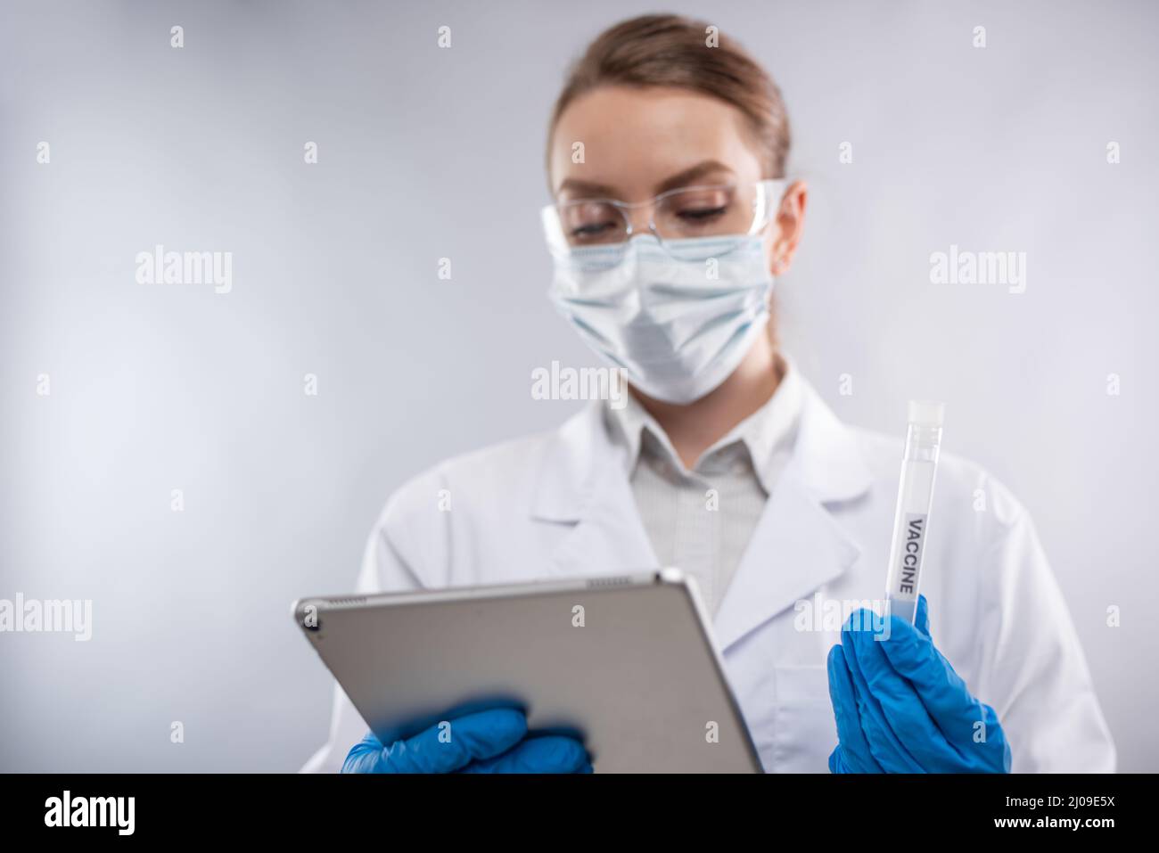 Female microbiologist in blue protective gloves and face mask holds ...
