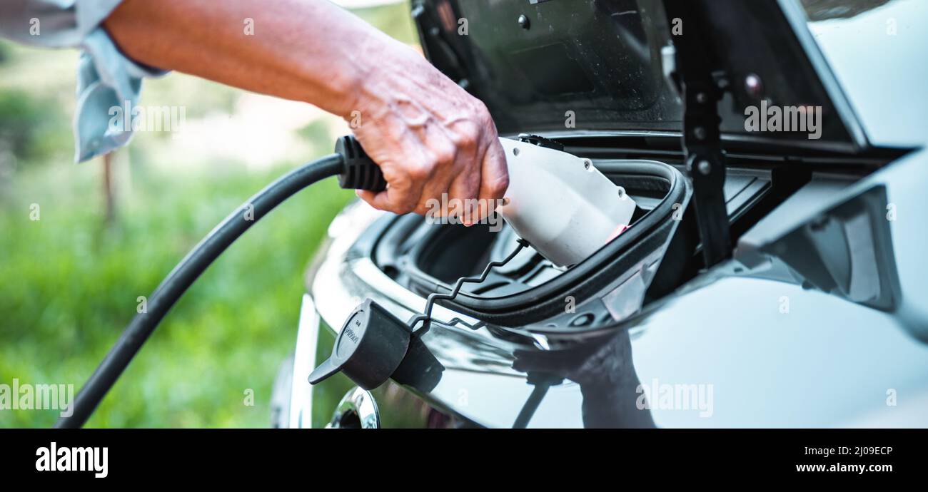 Human hand is holding electric car charging connect to electric car ...