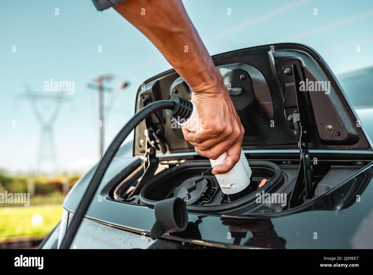 Human hand is holding electric car charging connect to electric car ...