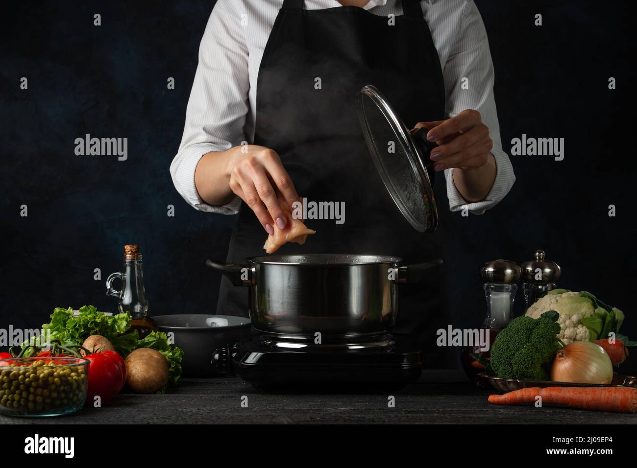 Professional chef pours chicken fillet into pan for cooking soup on ...
