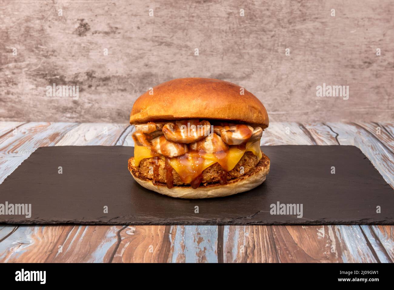 Vegan steak burger with stewed mushrooms and barbecue sauce on black ...