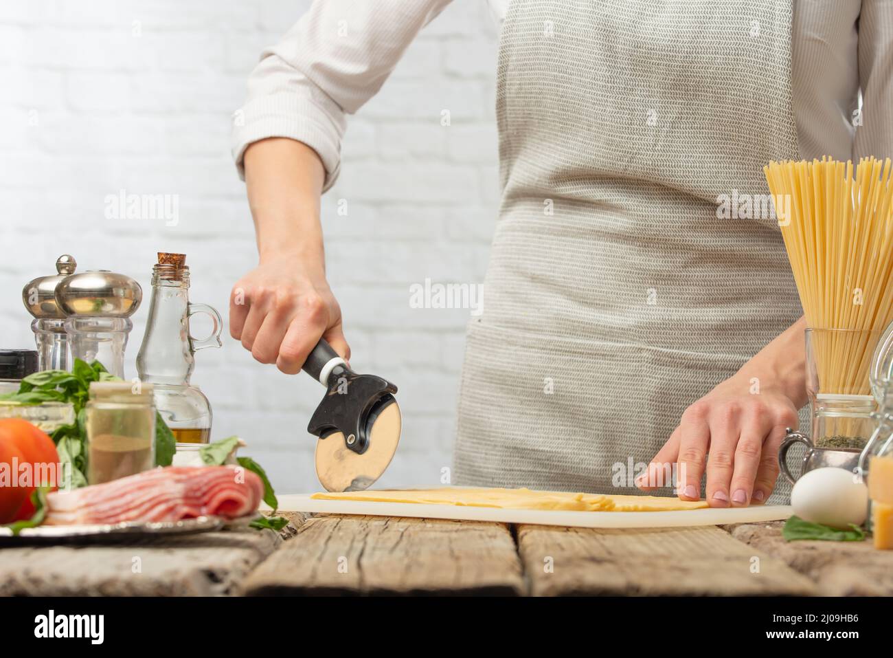 Chef in white uniform cuts with knife-wheel the dough. Backstage of ...