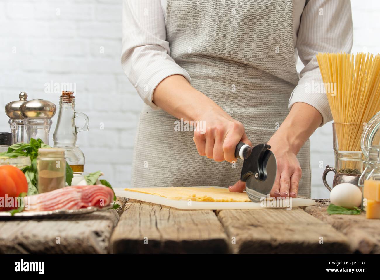 Chef in white uniform cuts with knife-wheel the dough. Backstage of ...