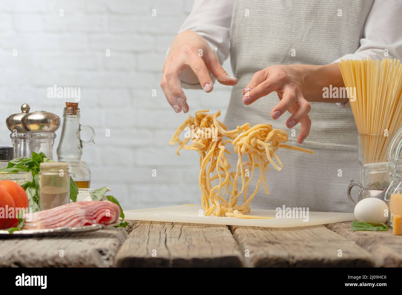 Chef in white uniform trows up raw dough. Backstage of cooking pasta ...