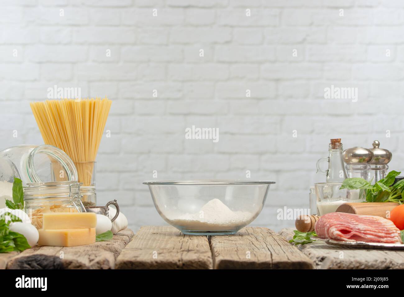 The glass bowl with flour for preparing dough on white background ...
