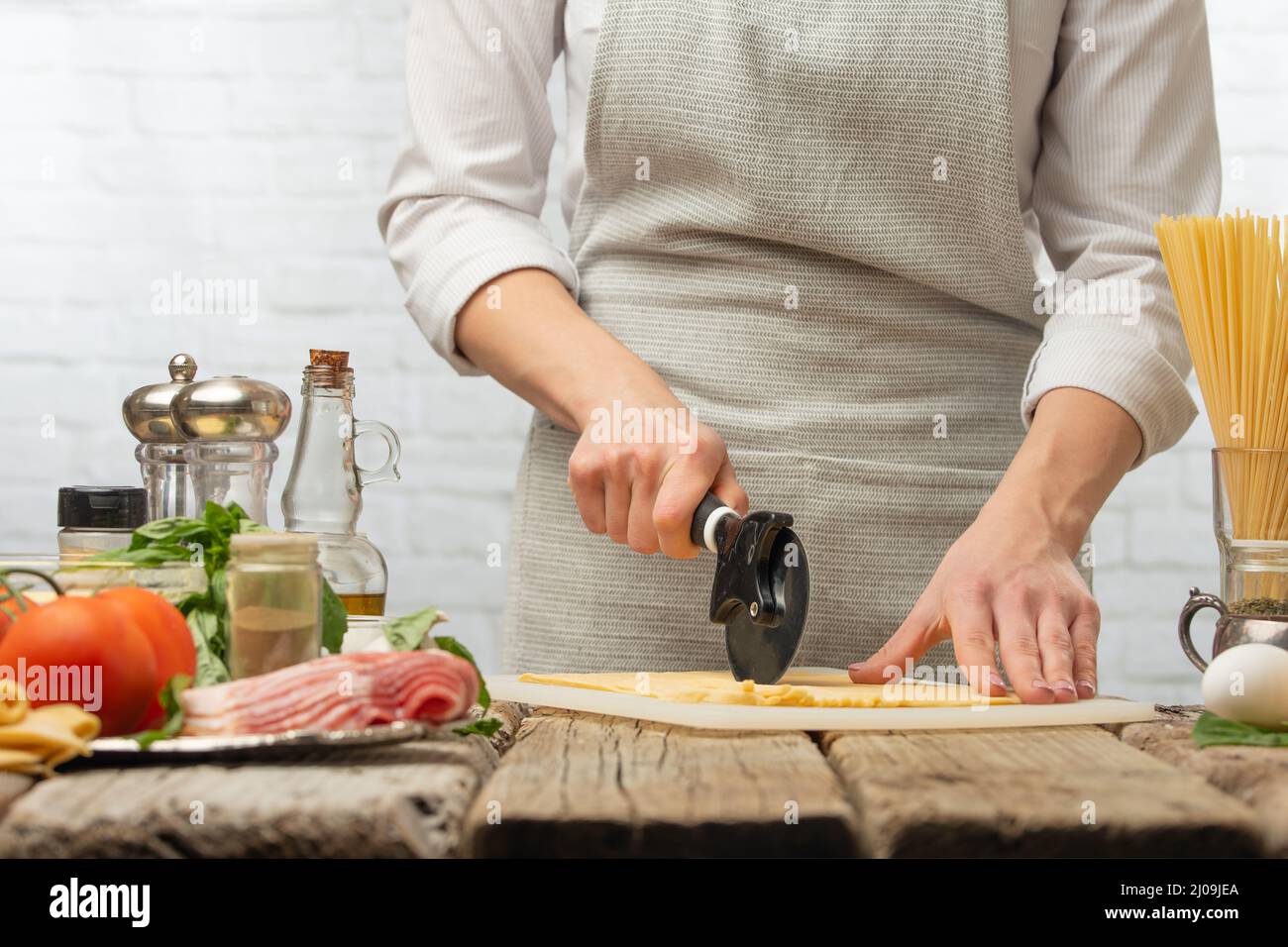 Professional chef cuts with knife wheel the dough for cooking pasta ...