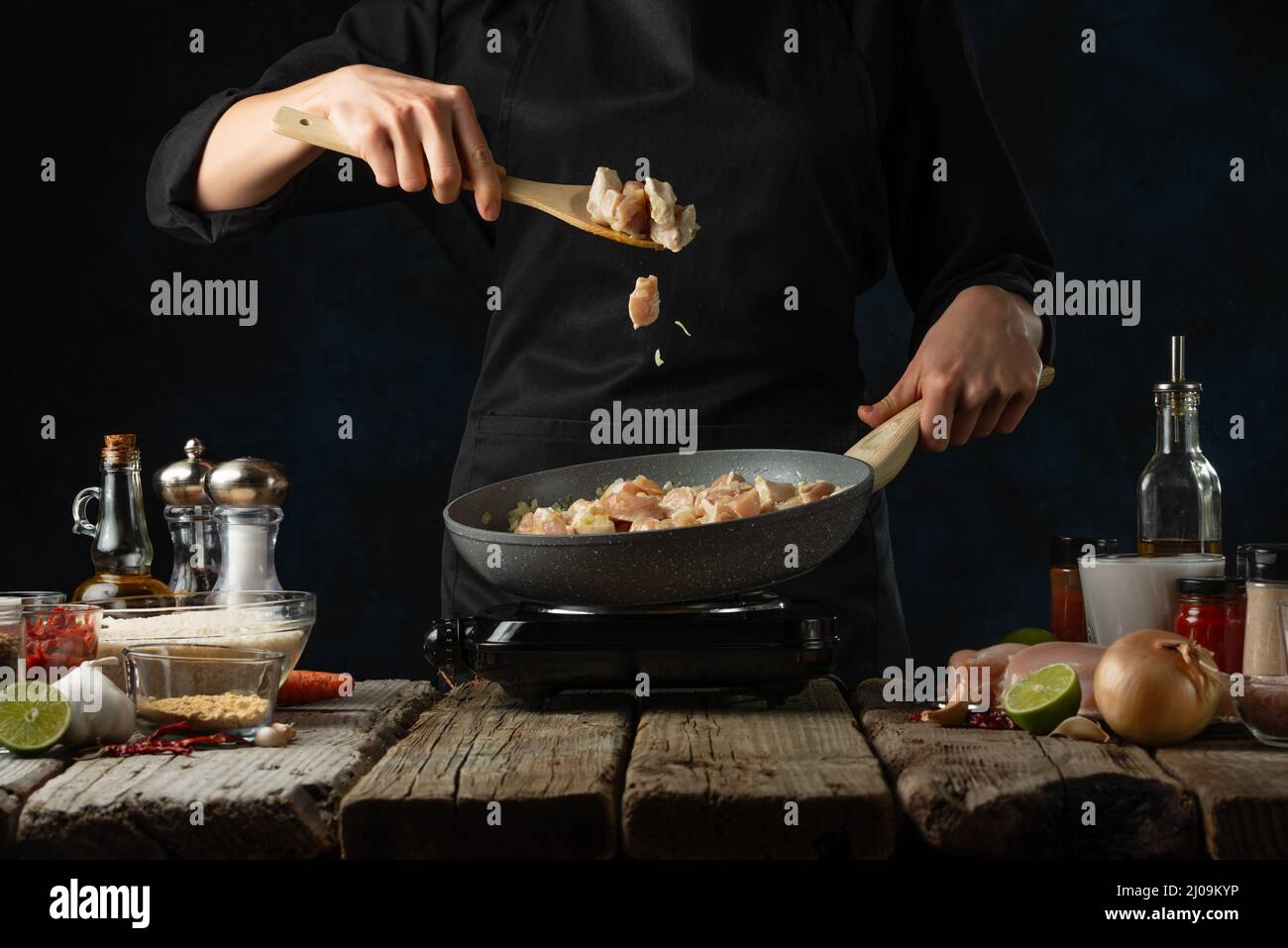 Professional chef stir frying chicken fillet in the pan. Backstage of ...