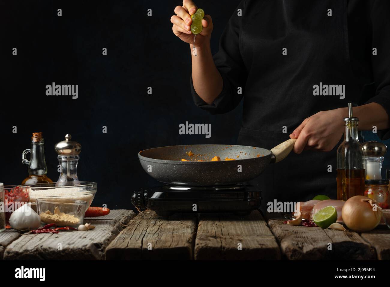Chef squeeze lime juice into pan with frying chicken fillet. Backstage ...