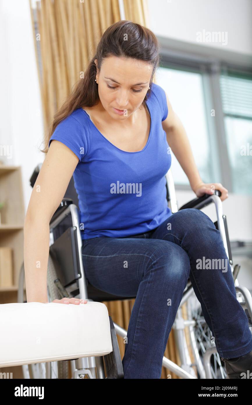 woman in wheelchair trying to sit on a sofa Stock Photo - Alamy