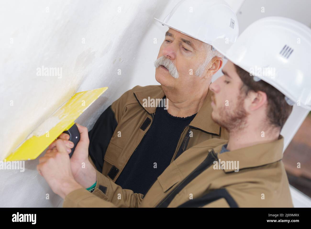 two working builders plastering a wall Stock Photo - Alamy