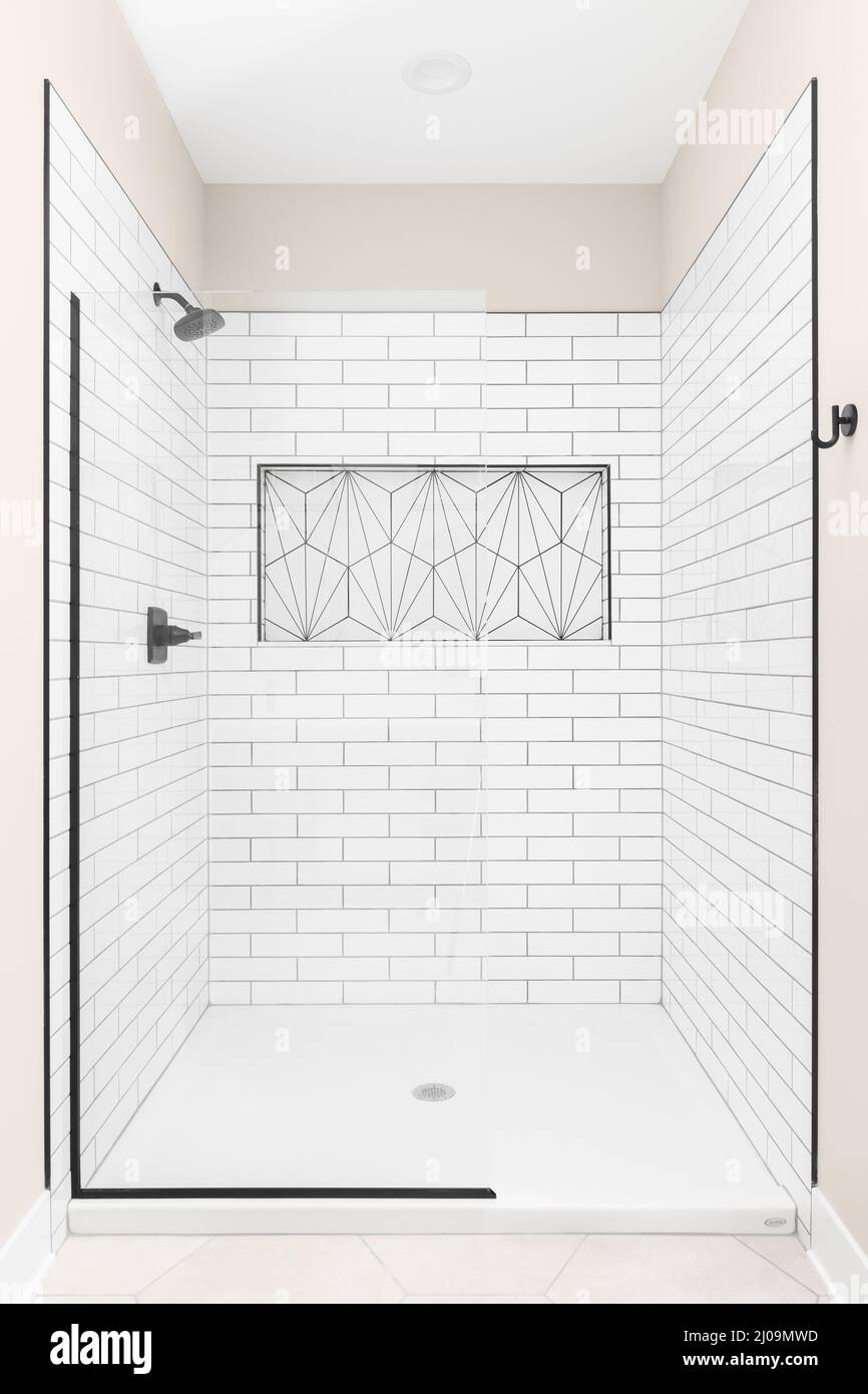 A renovated shower with white subway tiles, glass wall, black faucet ...