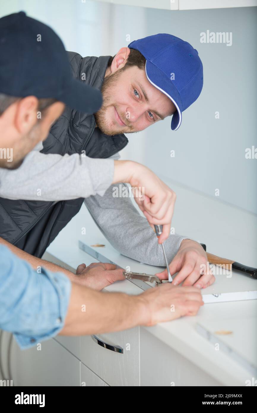 man assembling hinge on kitchen cupboard using screwdriver Stock Photo ...