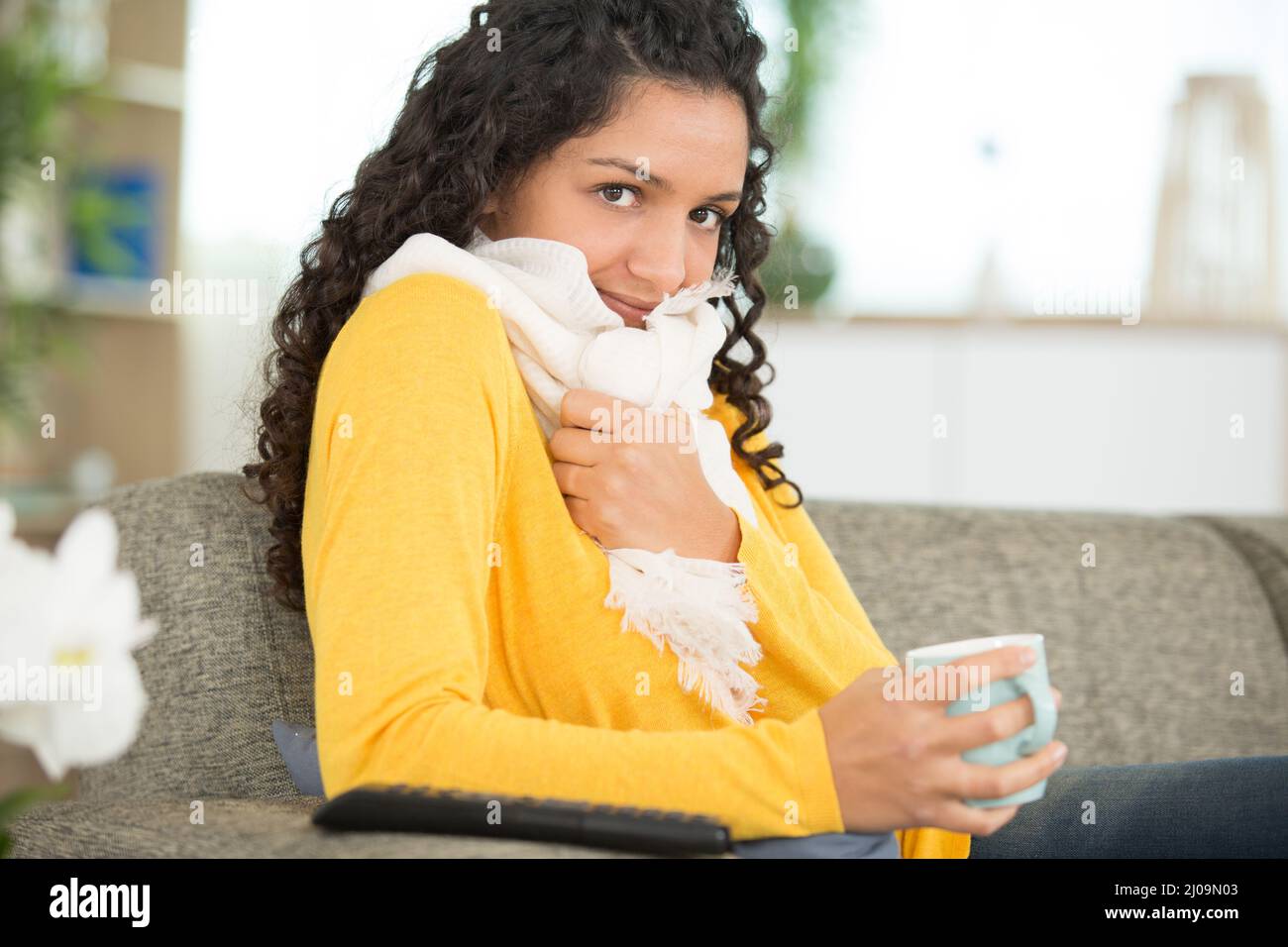 happy young woman sitting on a couch drinking tea Stock Photo - Alamy