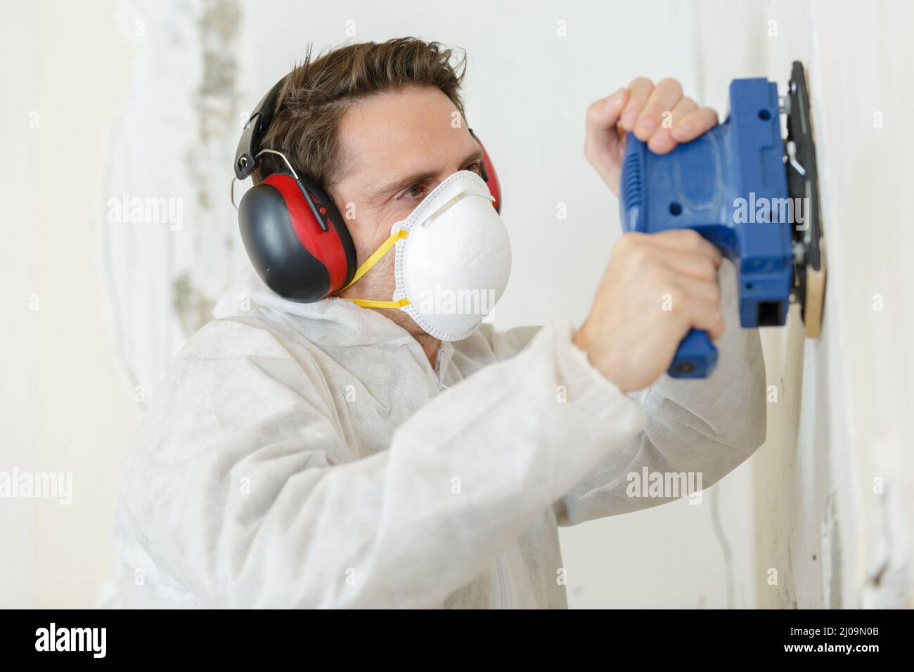 a man sanding a wall Stock Photo - Alamy