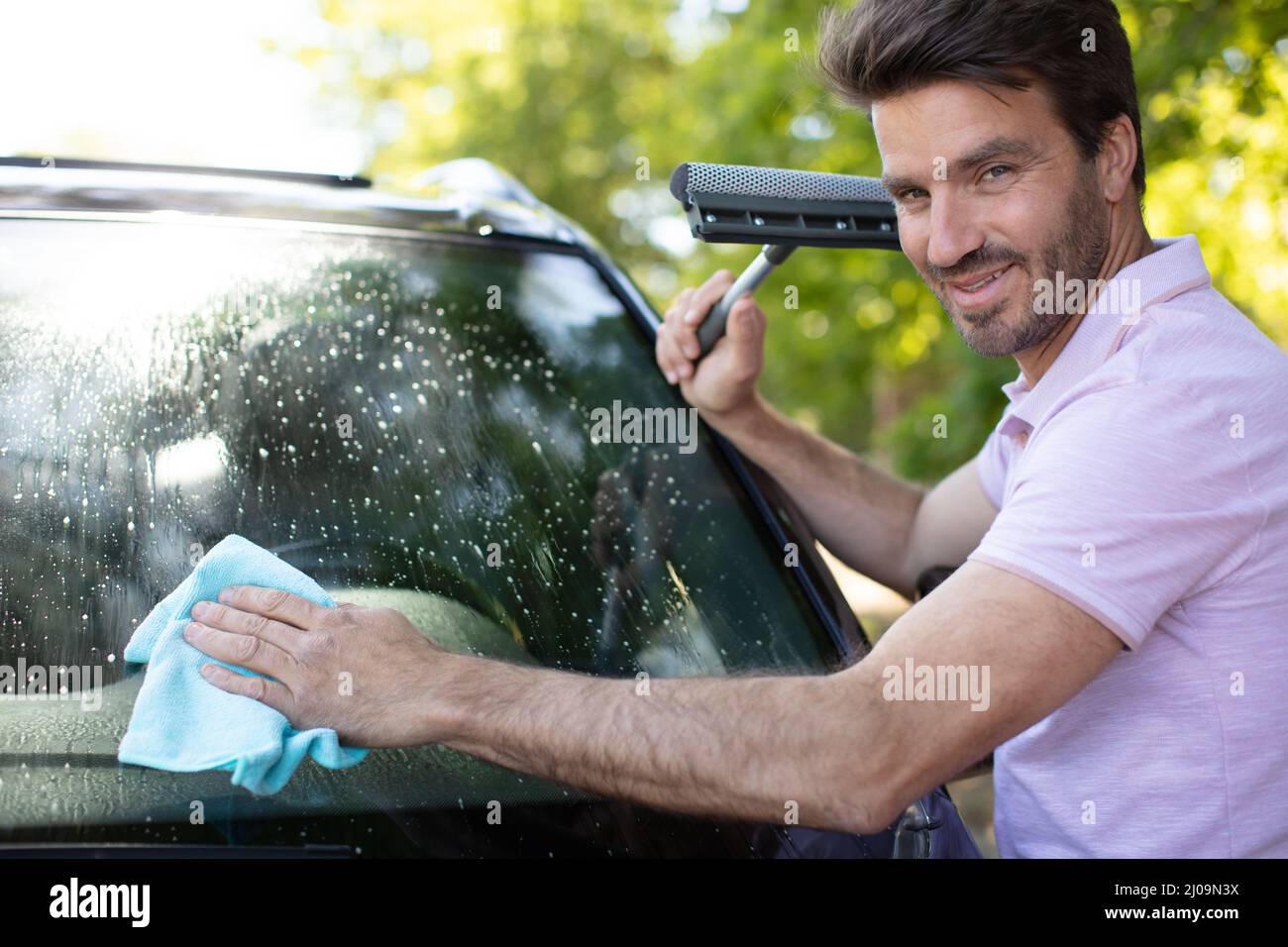 happy man holding squeegee while cleaning car window Stock Photo - Alamy