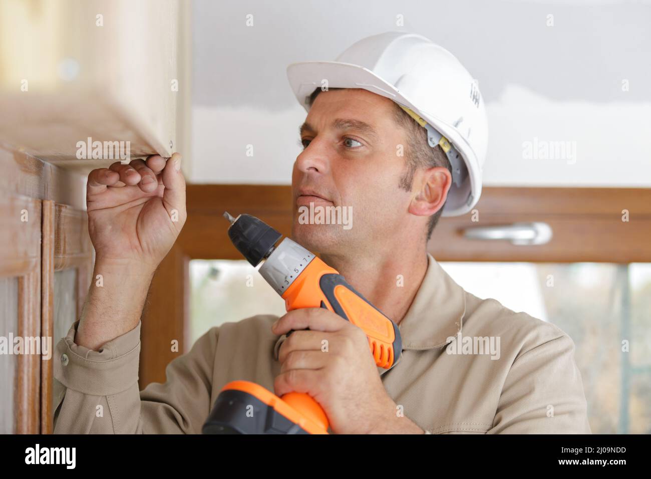 man drilling a hole in a window frame Stock Photo - Alamy