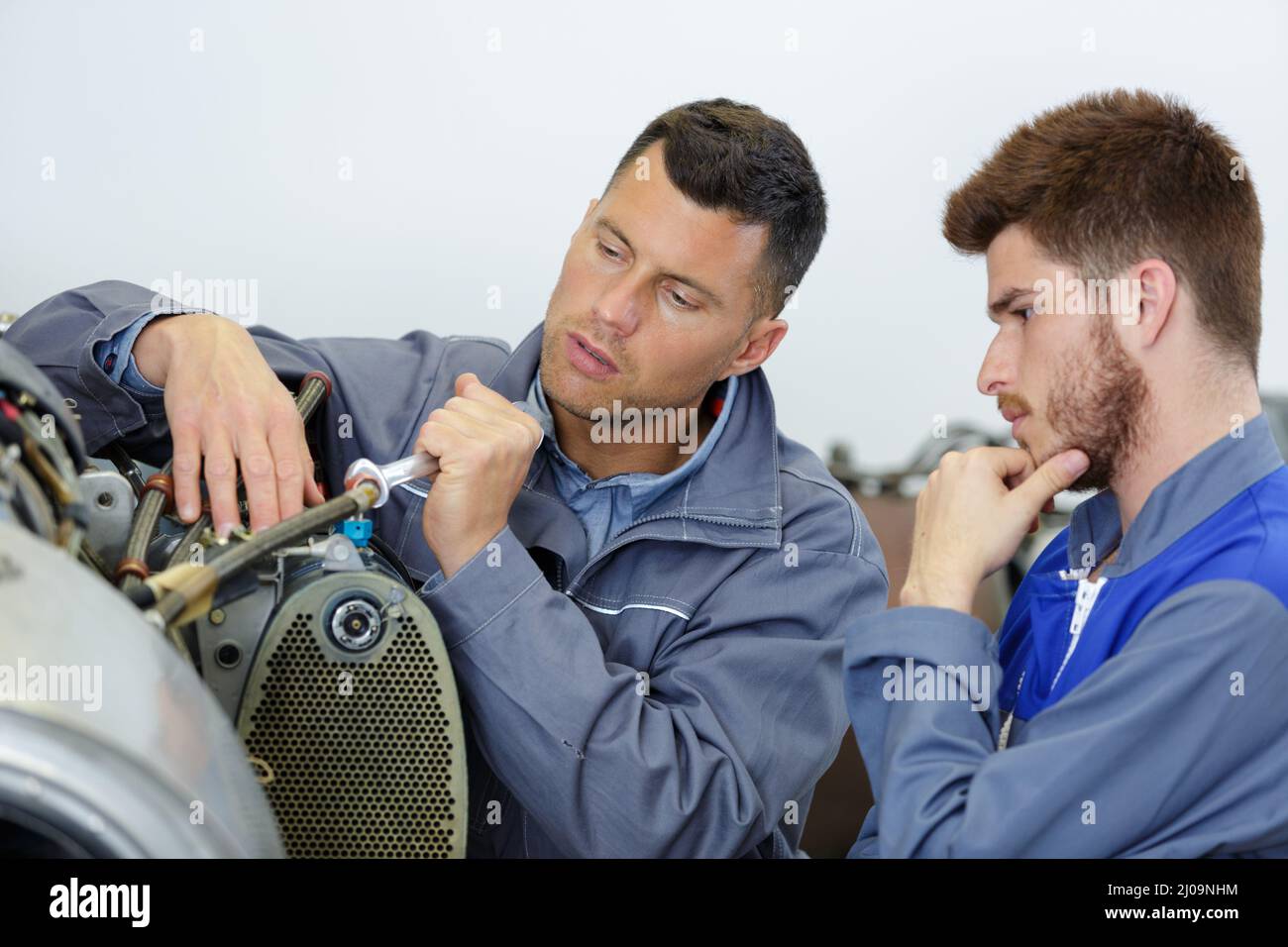 young mechanic watching how to fit hose Stock Photo - Alamy