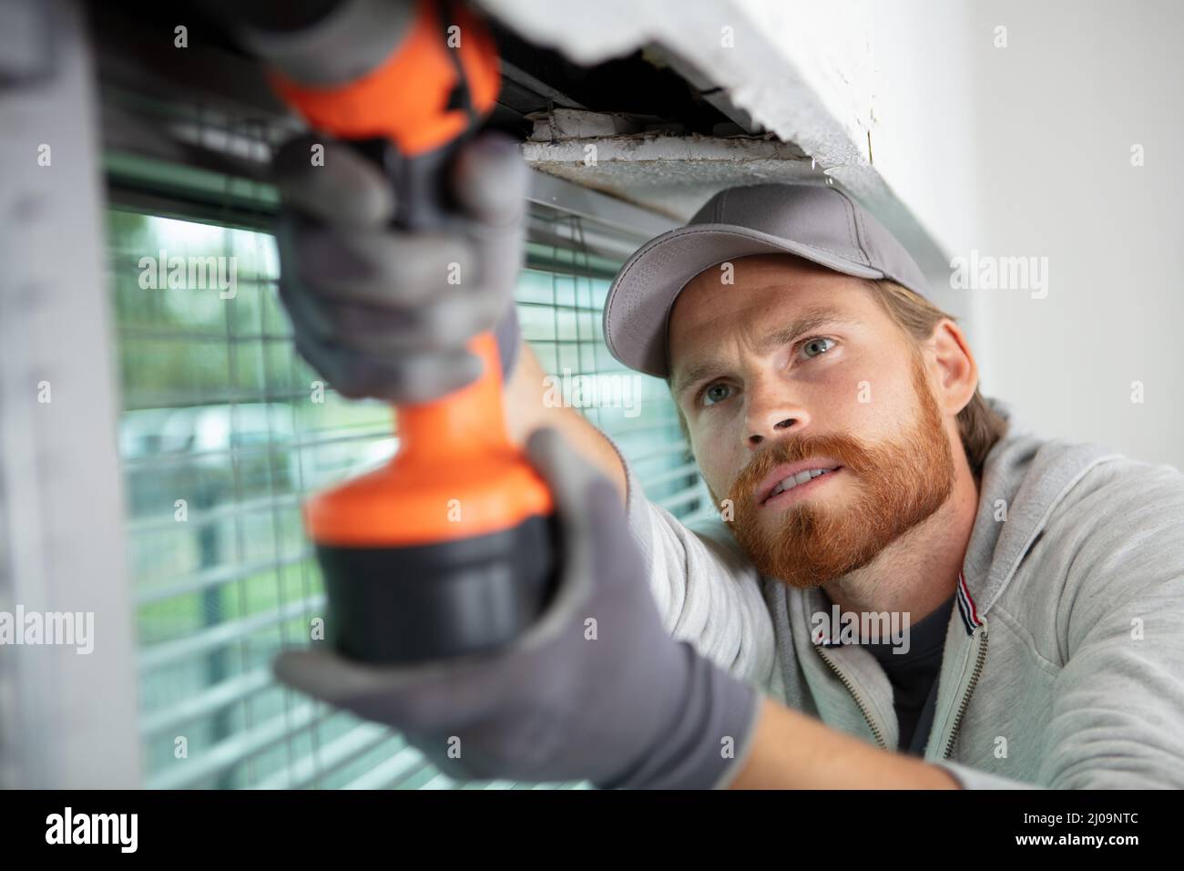 construction worker using drill to install window Stock Photo - Alamy