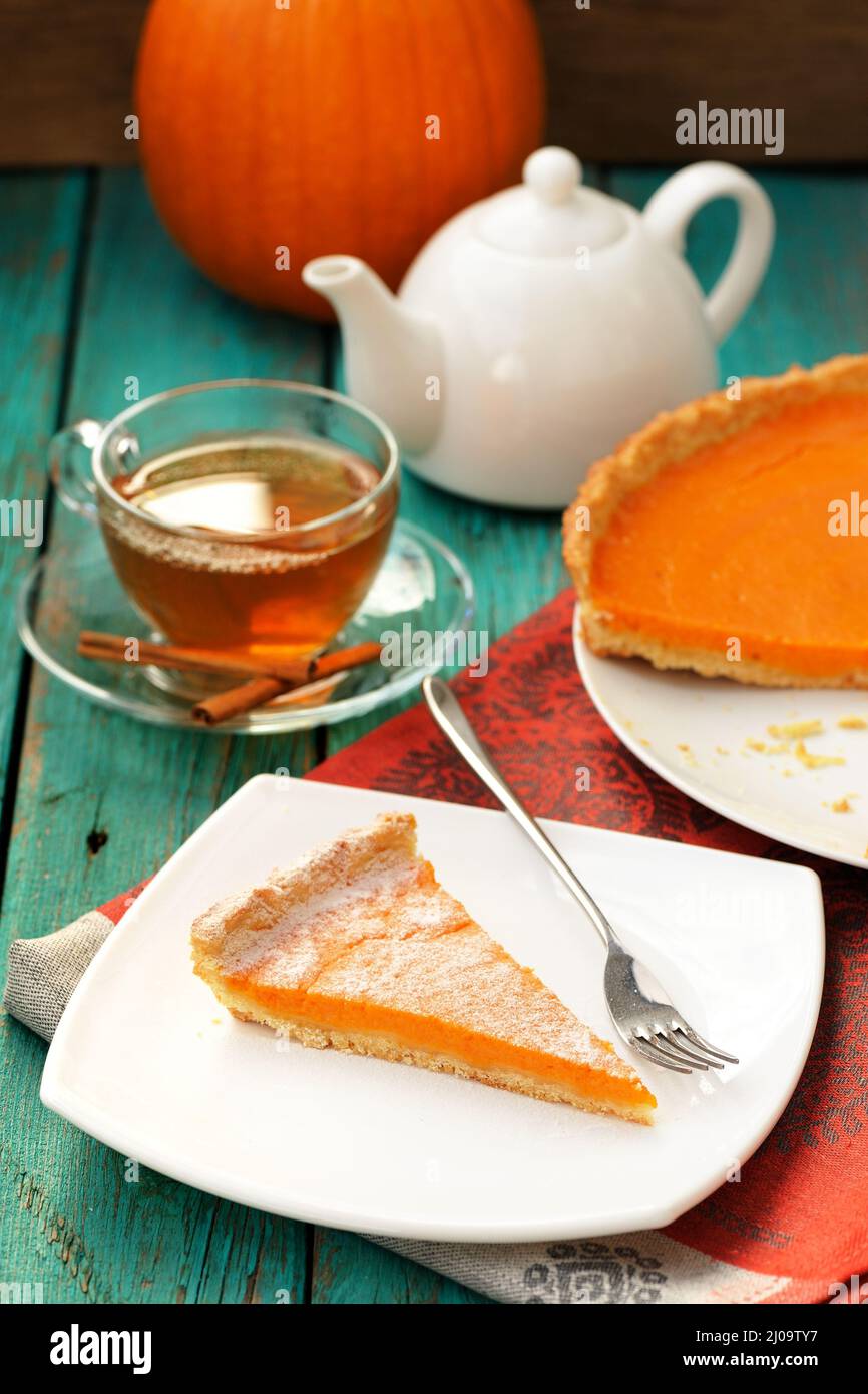 Pumpkin pie, tea in glass cup, white teapot and fresh pumpkin on ...