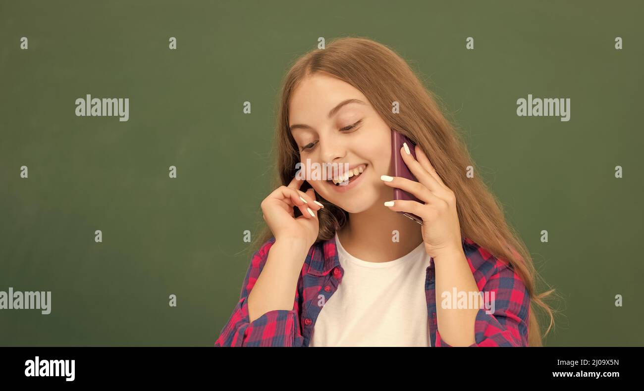 happy kid speaking on smartphone in classroom at blackboard, copy space ...
