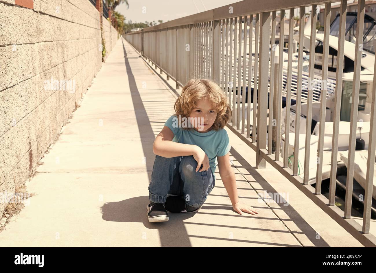 Boy child take short break hunkering down on promenade, rest Stock ...