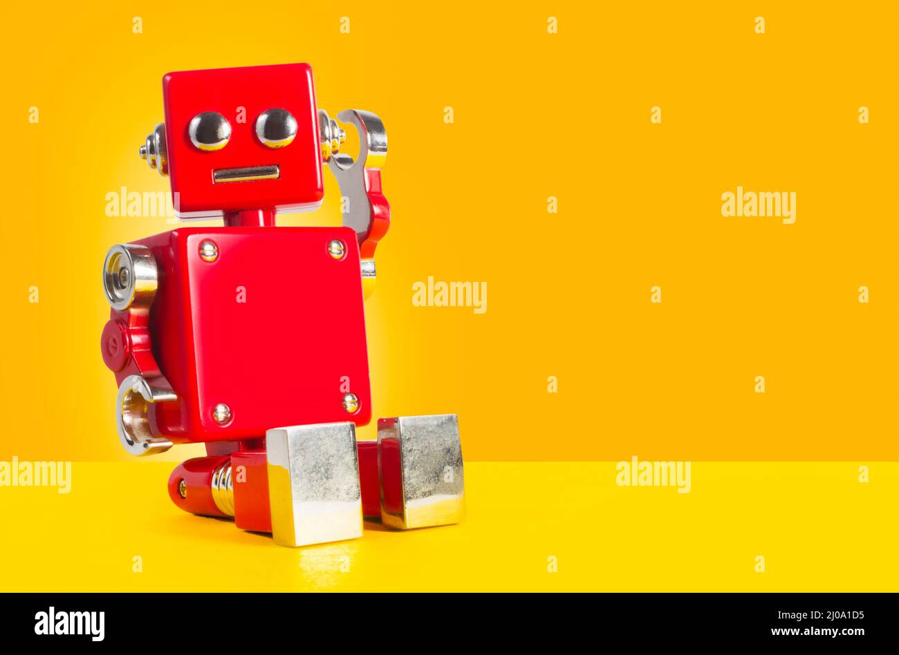 Red colored old fashioned retro metal toy robot sitting on orange ...