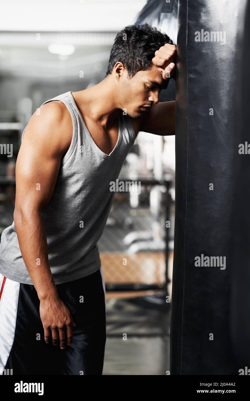 Exhausted after a workout. A muscular young man leaning against a ...
