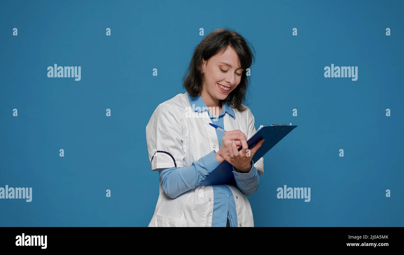 Female scientist taking notes on clipboard documents, writing formula ...