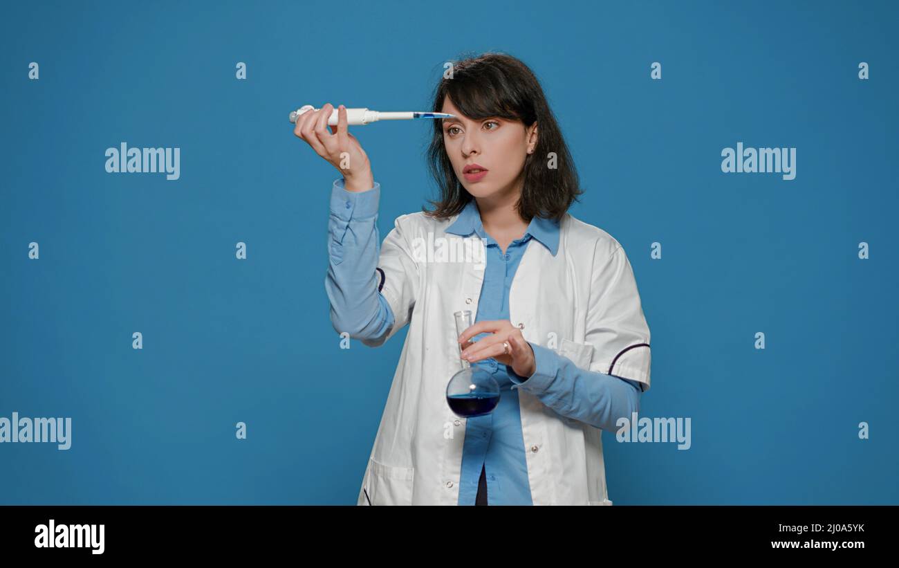 Woman scientist using micro pipette to drip liquid in beaker, doing ...
