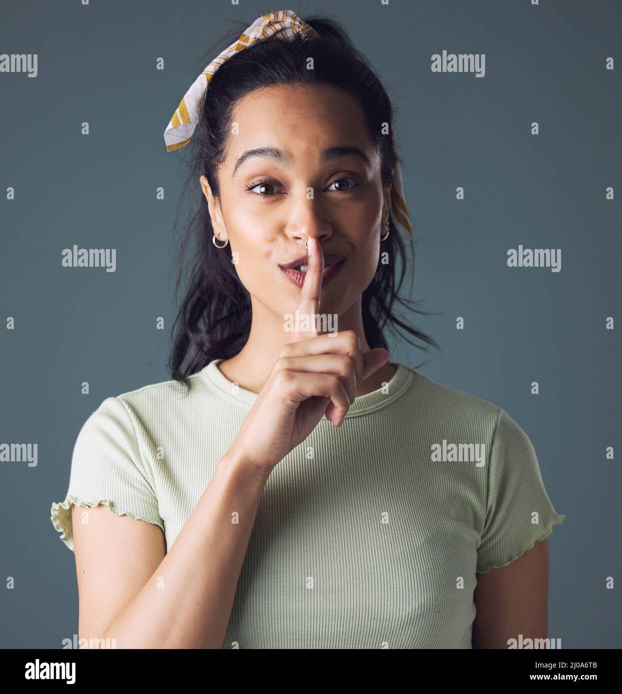 You cant tell anyone. Studio shot of a young woman posing with her ...