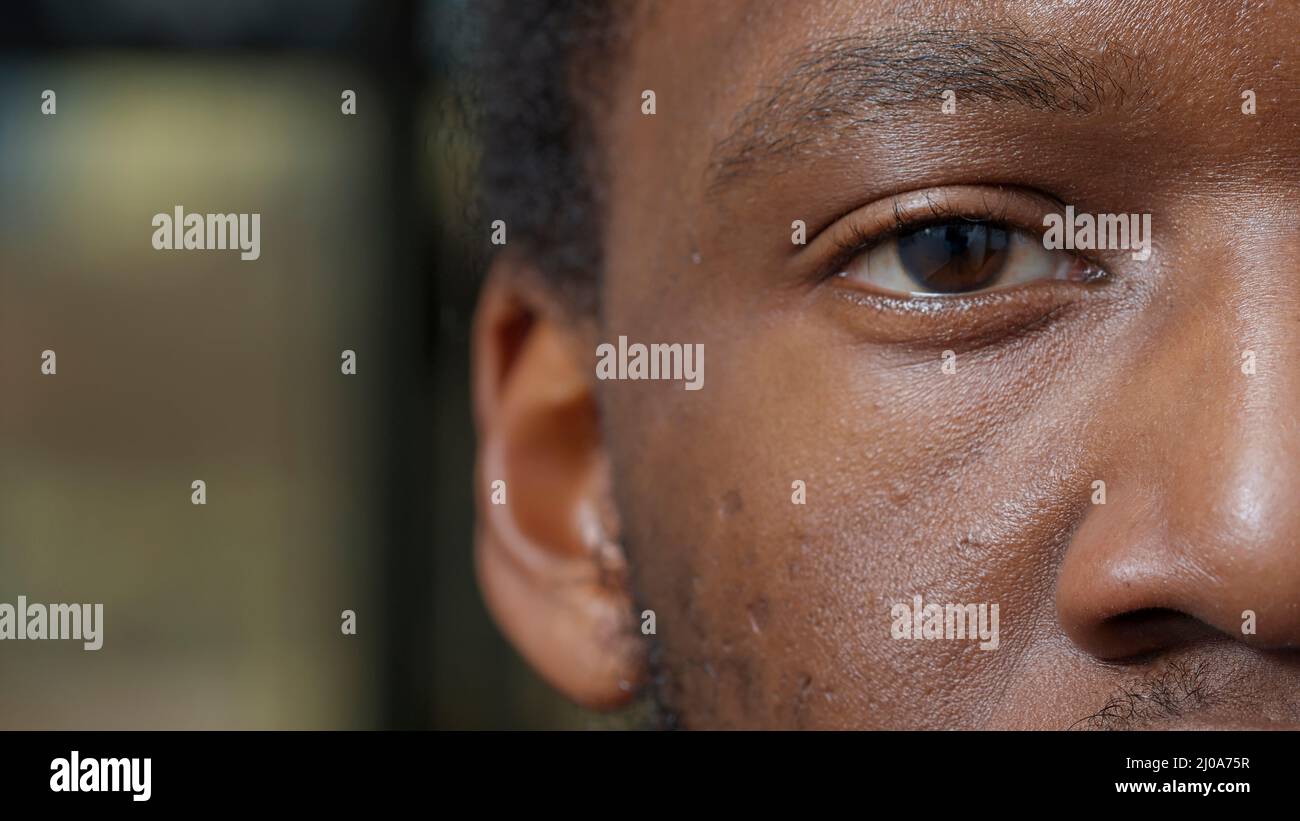 Macro shot of man showing half of face and one eye, looking at camera ...