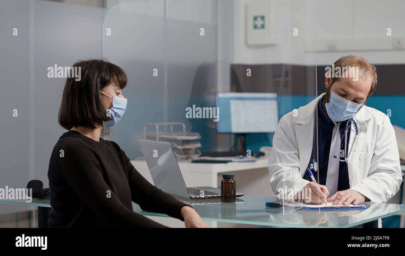 Doctor taking notes and giving prescription paper to female patient ...