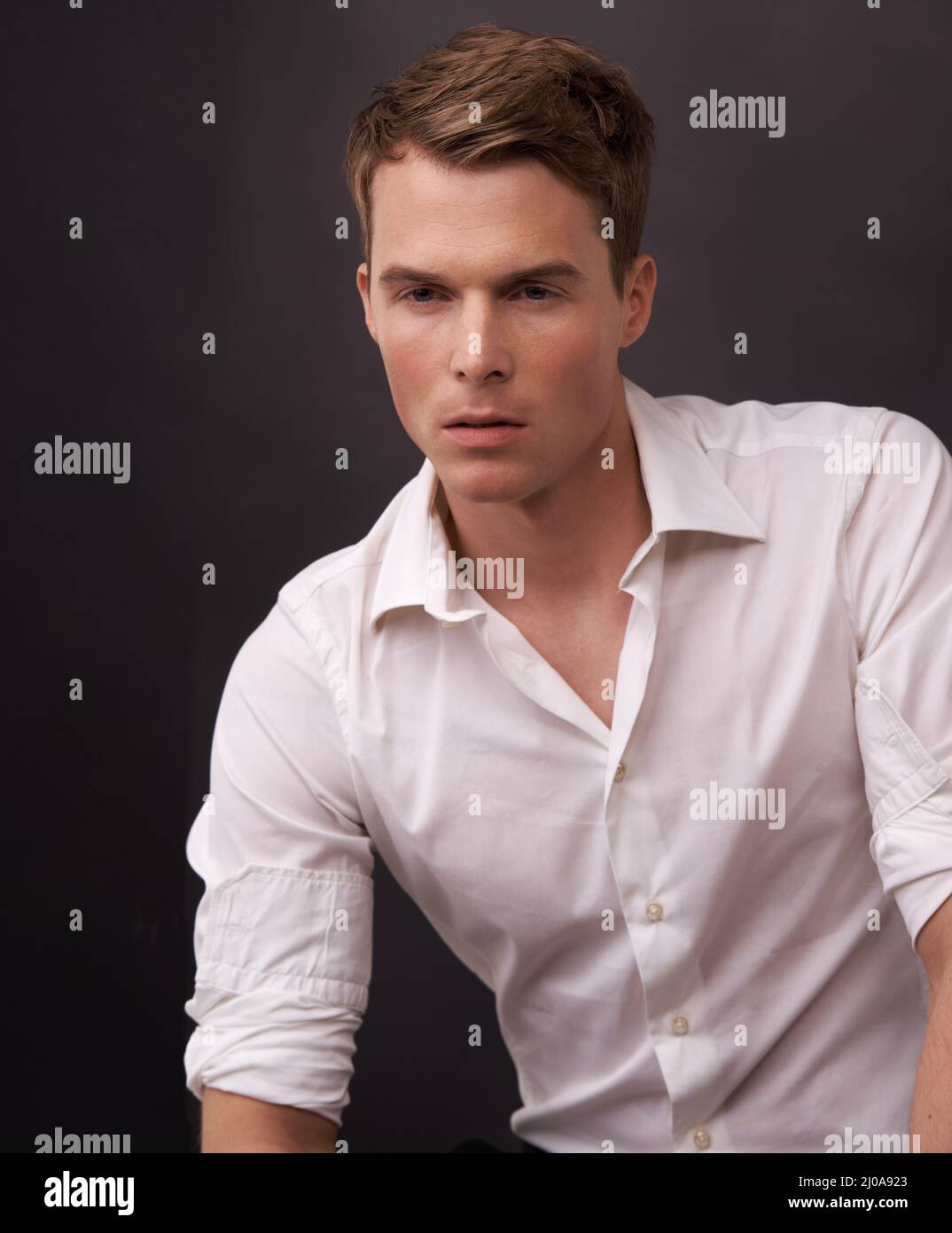 Handsome and reserved. A handsome young man in a white shirt against a ...