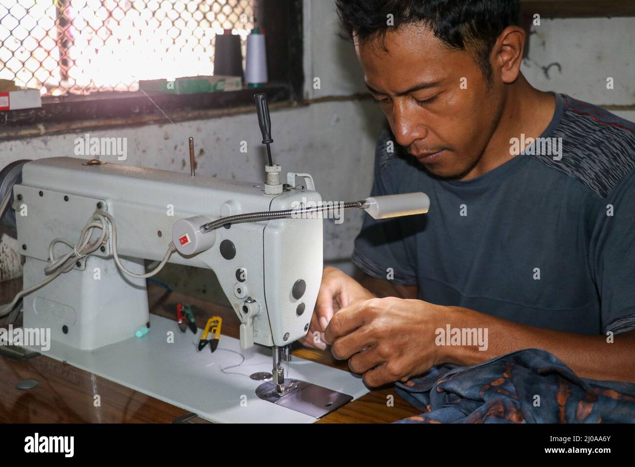 Asian man sews clothes on a sewing machine. Middle aged male tailor ...