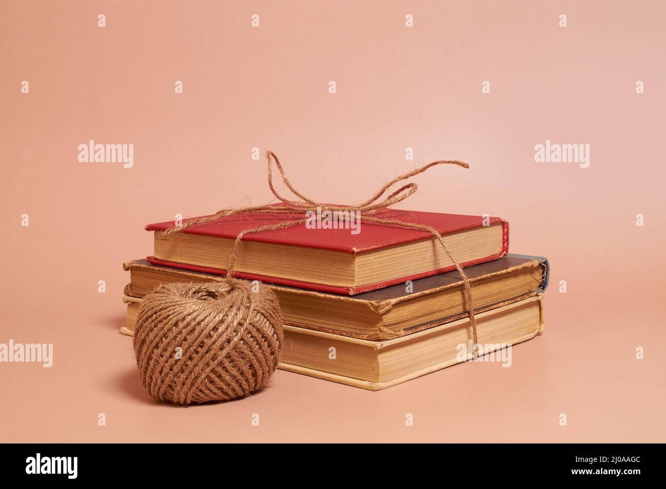 A stack of old battered books tied with jute rope, a coil of jute rope ...