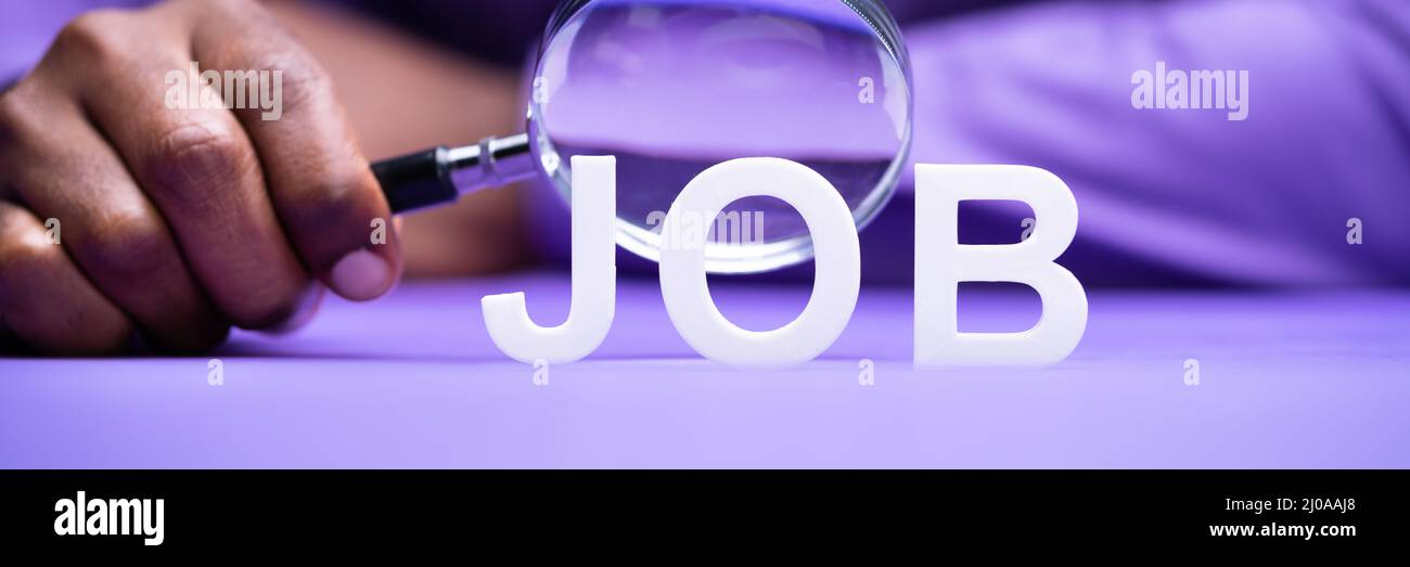 Person's Hand Looking At Job Through Magnifying Glass On Desk Stock ...