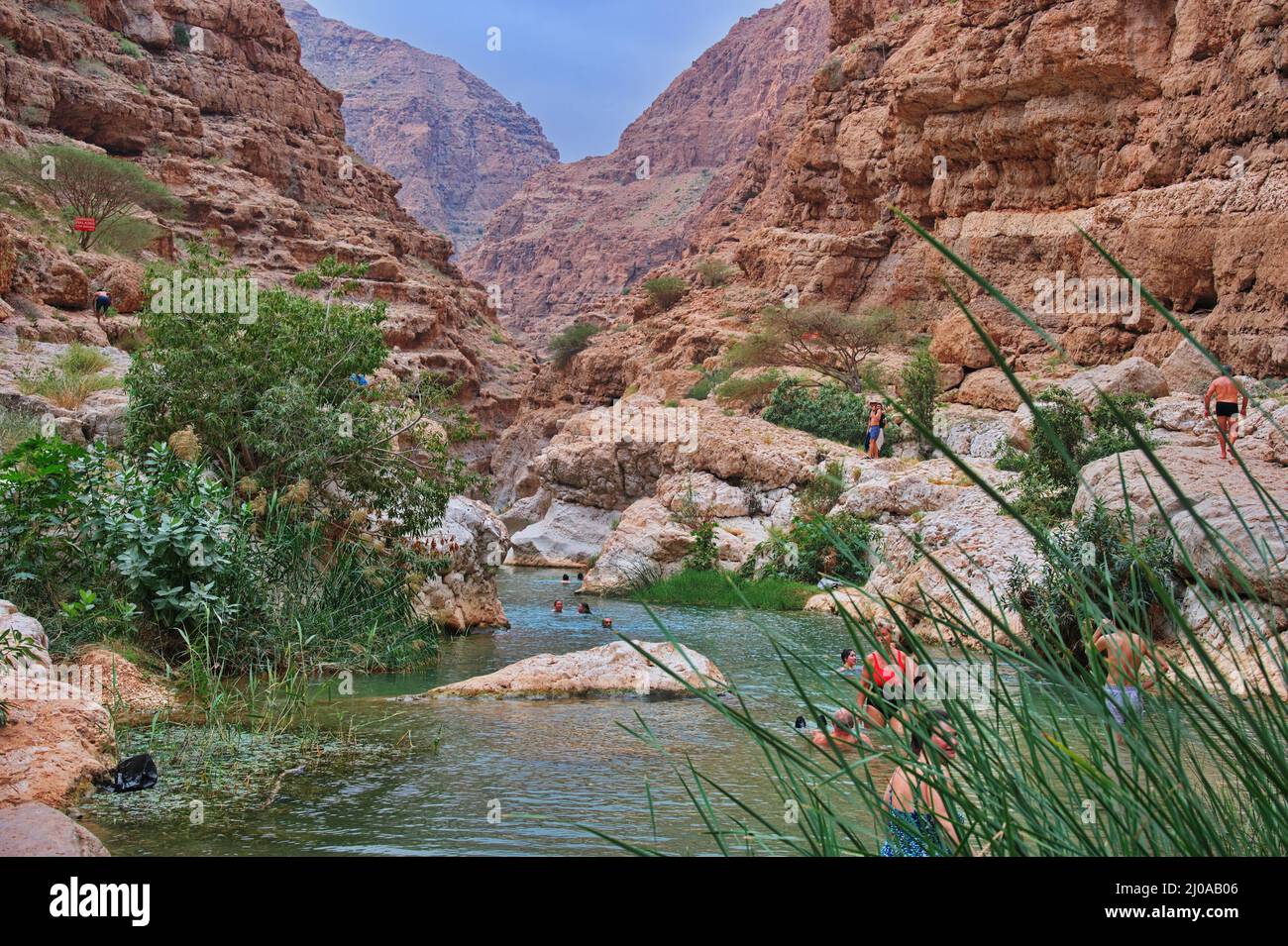 Tourists swimming in lagoon with turquoise water in Wadi Shab in Oman ...