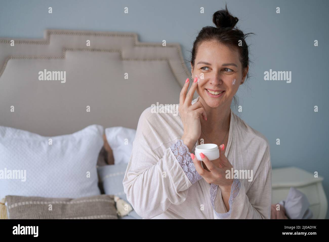 Happy woman doing routine skin care at home with beauty products. Woman ...