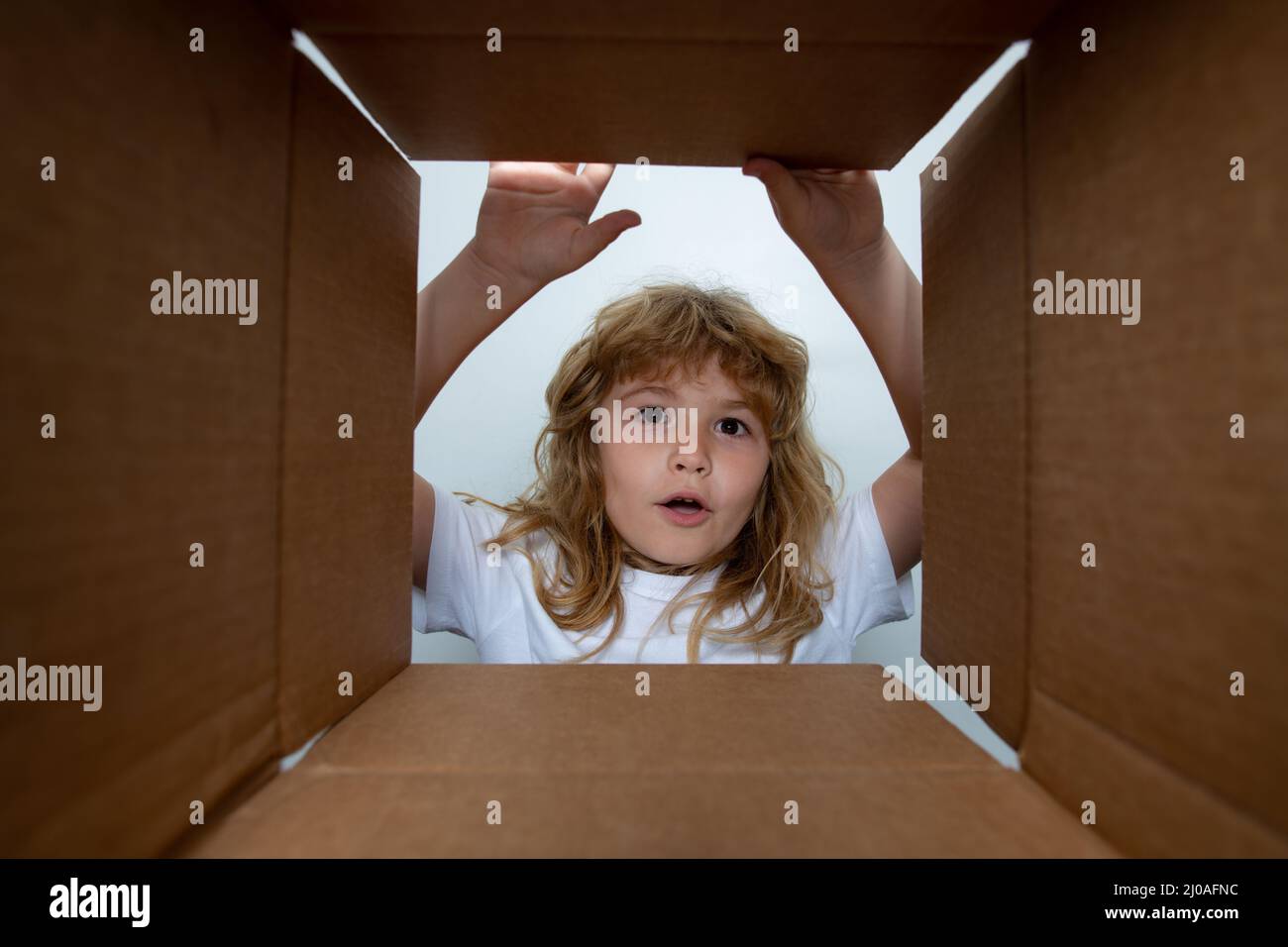 Child surprisedand shocked looking inside cardboard box, bottom view ...