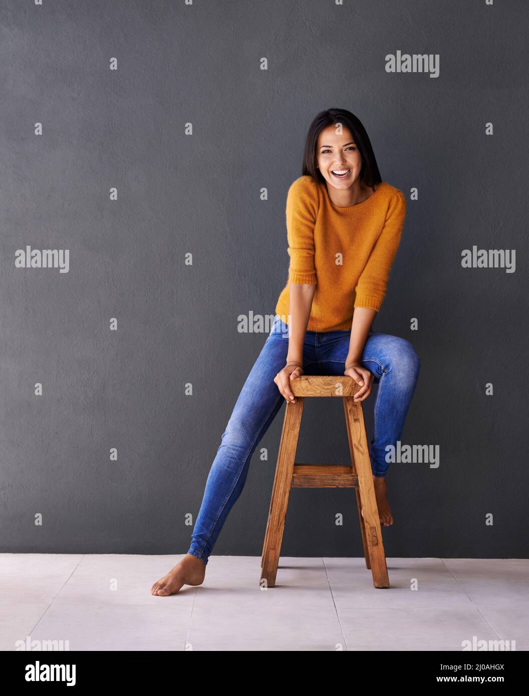 Positive and carefree. Portrait of a happy young woman sitting on a ...