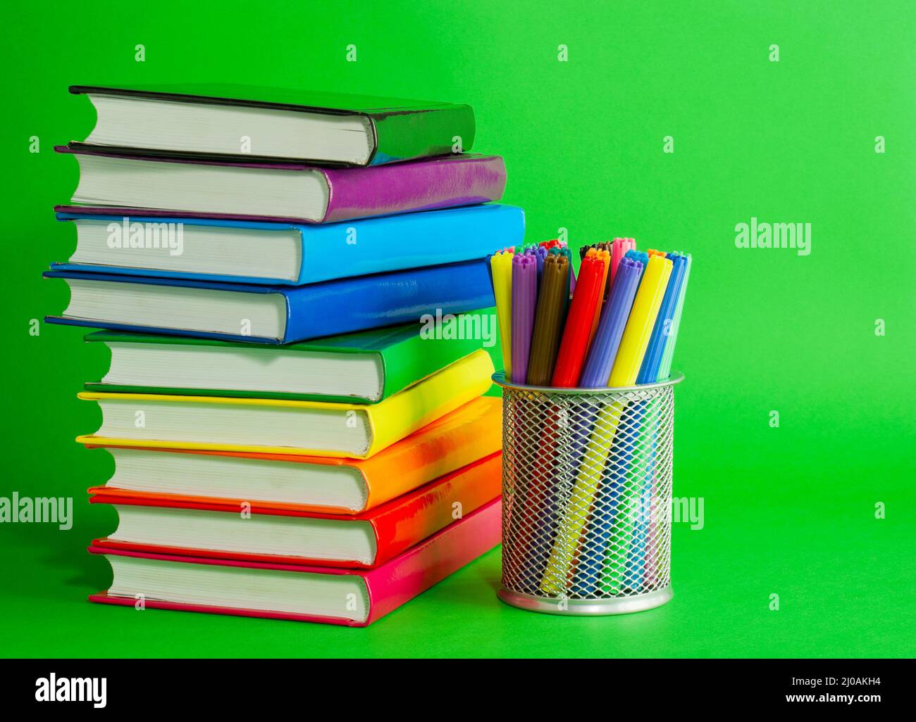 Stacks of colorful books and socket with felt pens Stock Photo - Alamy