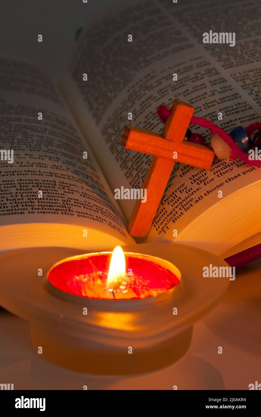 Open Bible with cross and burning candles Stock Photo - Alamy