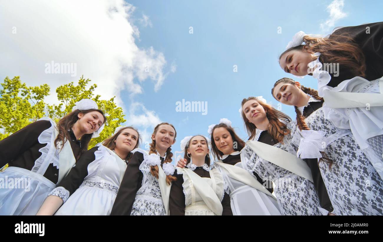 Happy Russian female graduates hug and wave their hands on graduation ...