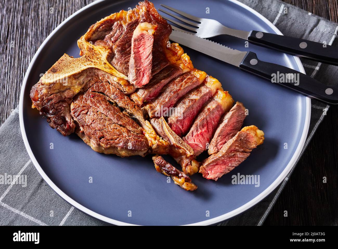 roast sliced porterhouse steak, t-bone steak on a plate with steak ...