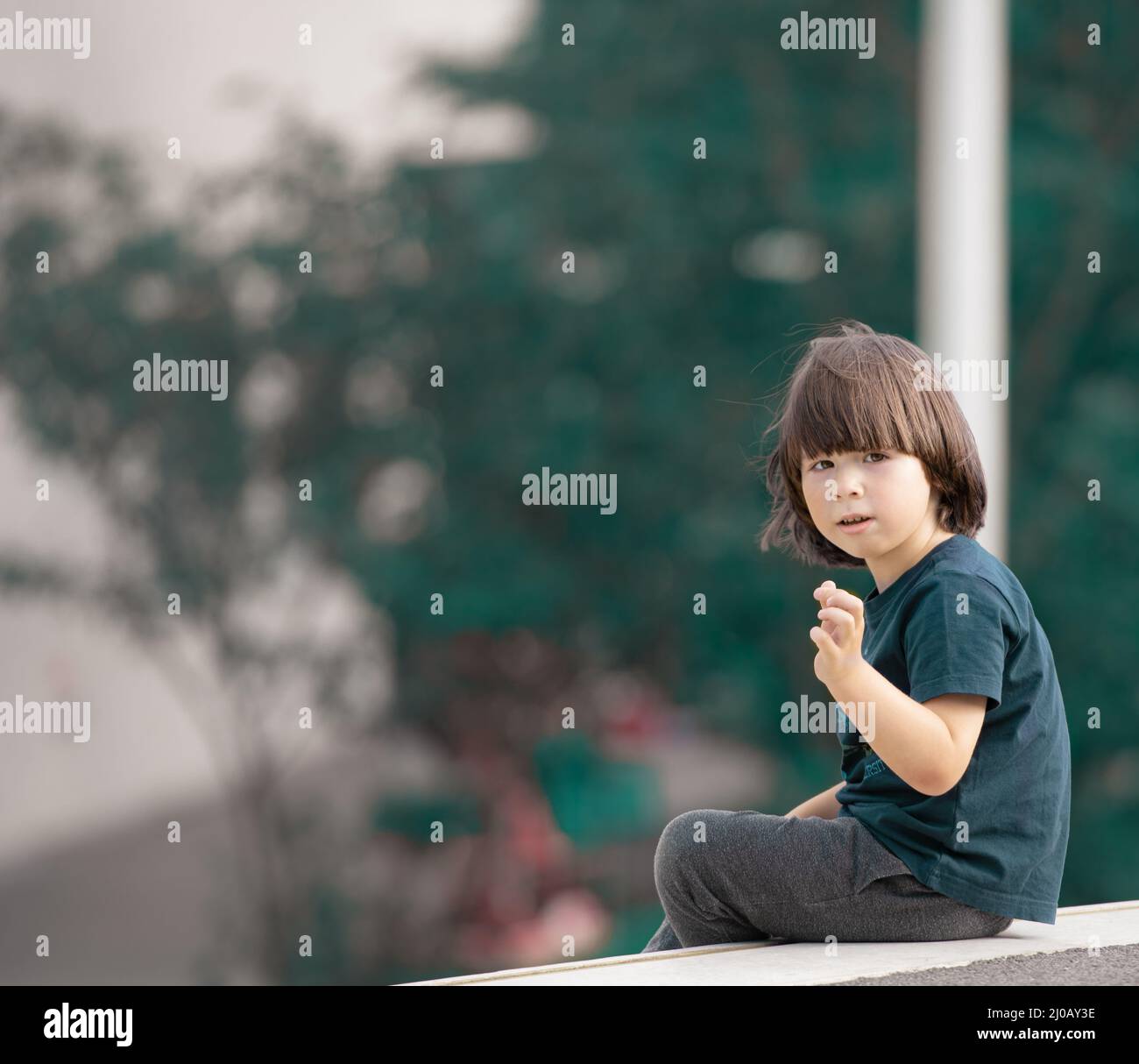Child sits on the edge in the garden and looking back Stock Photo - Alamy