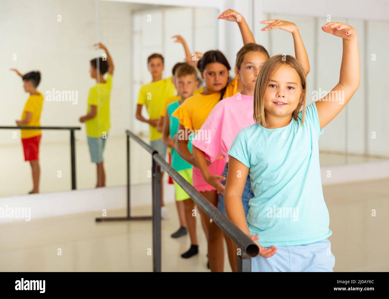 Children standing along ballet bar in dance studio during dance class ...