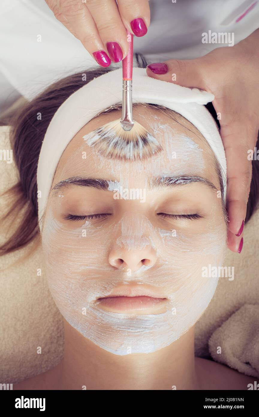 Face mask. Cosmetician applying facial beauty mask for woman at spa ...