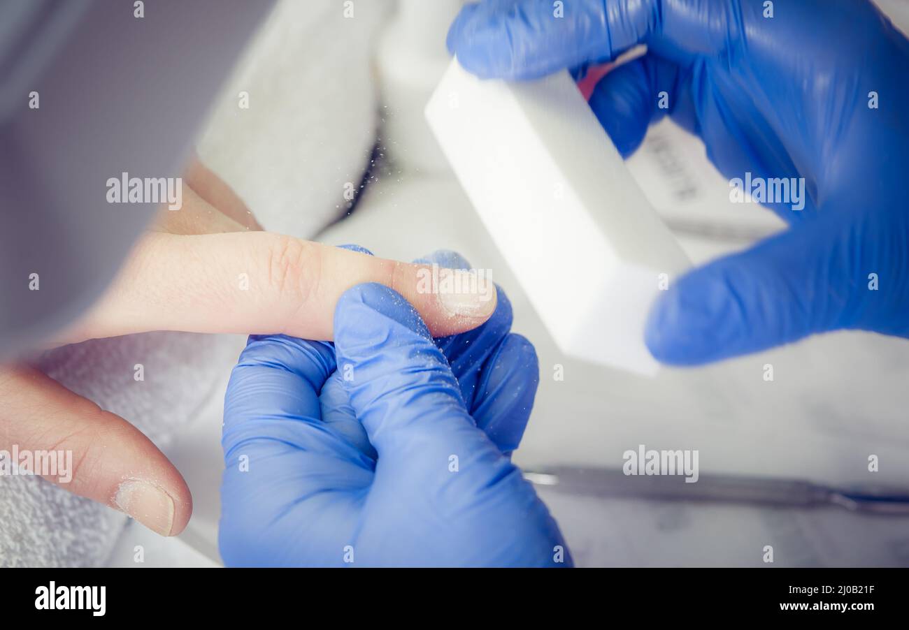 Finger nail treatment, grinding and polishing in beauty salon. Manicure ...