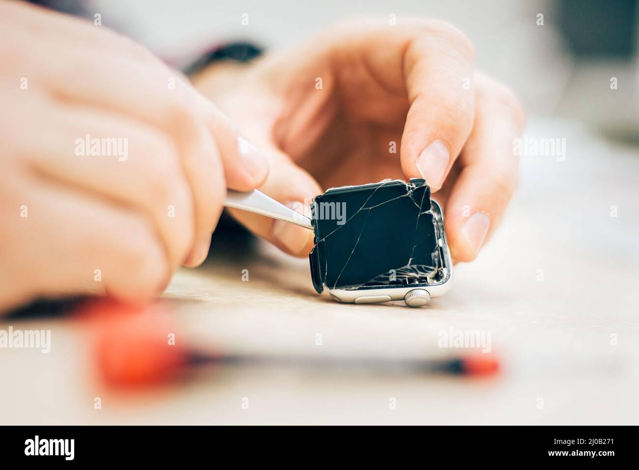 Technician repairs smartwatch with tweezers in electronic smartphone ...